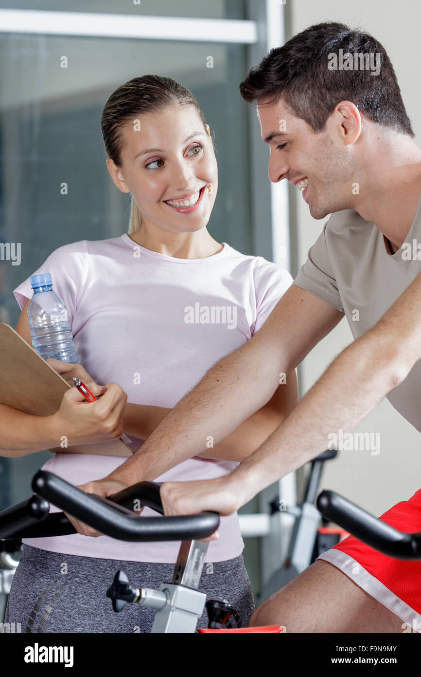 young man on cycle machine with trainer Stock Photo - Alamy