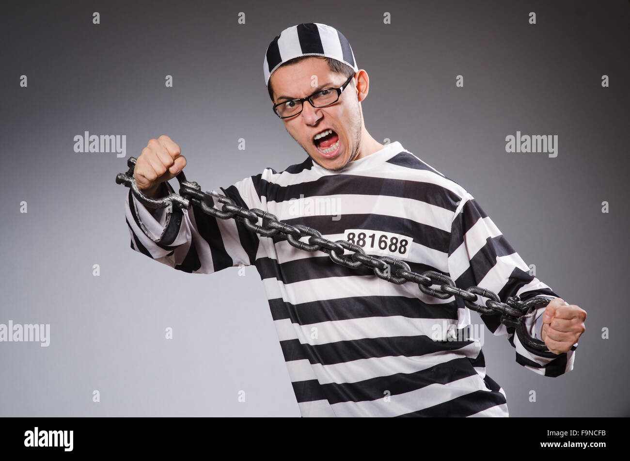 Young prisoner in chains against gray Stock Photo - Alamy