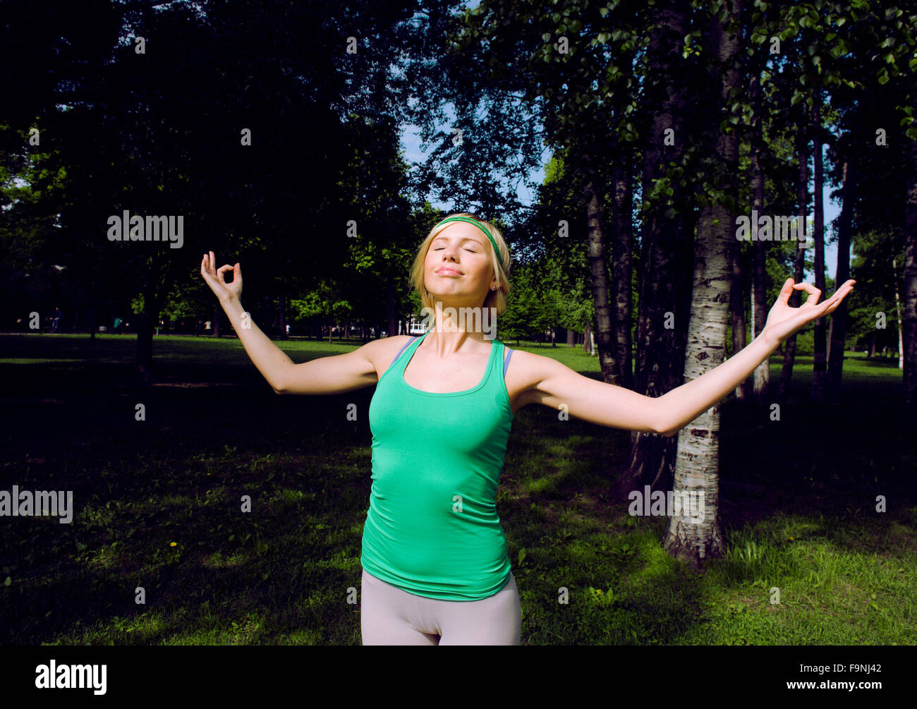 blonde real girl doing yoga in green park, gymnastic head over hills ...