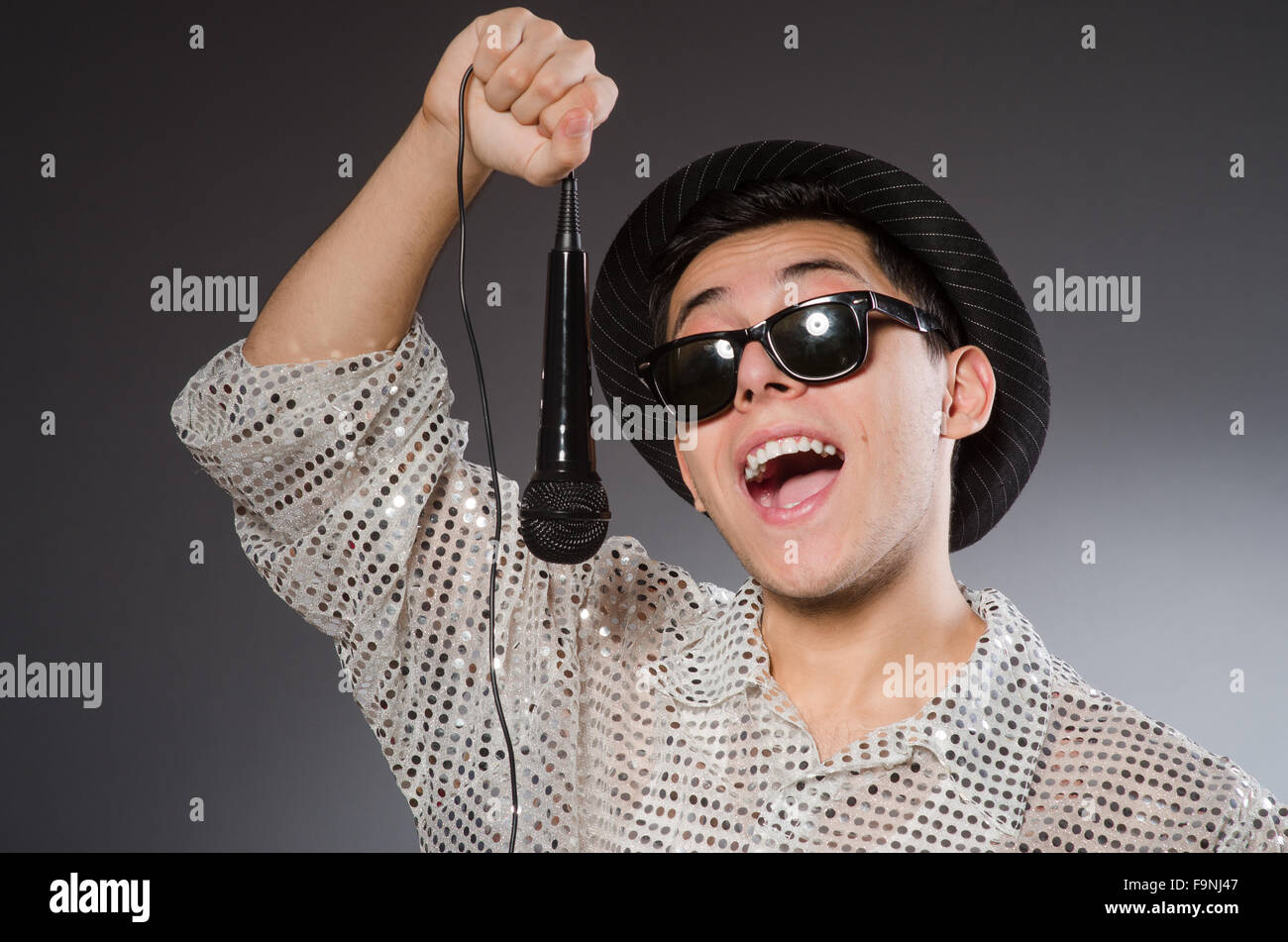 Young cheerful singer with microphone Stock Photo - Alamy