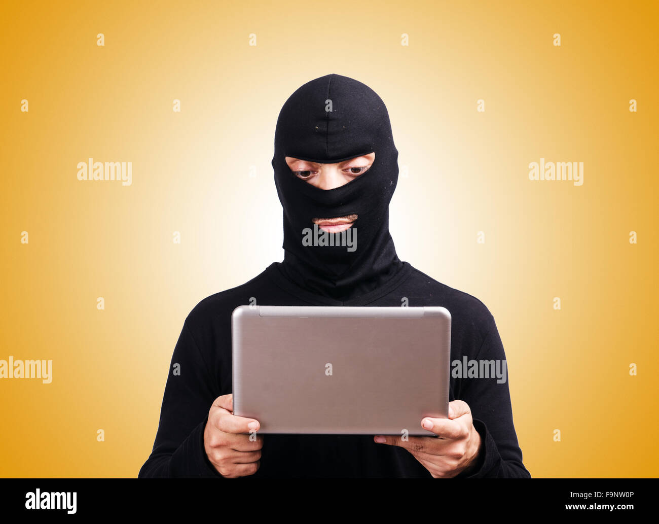 Hacker with computer wearing balaclava Stock Photo - Alamy