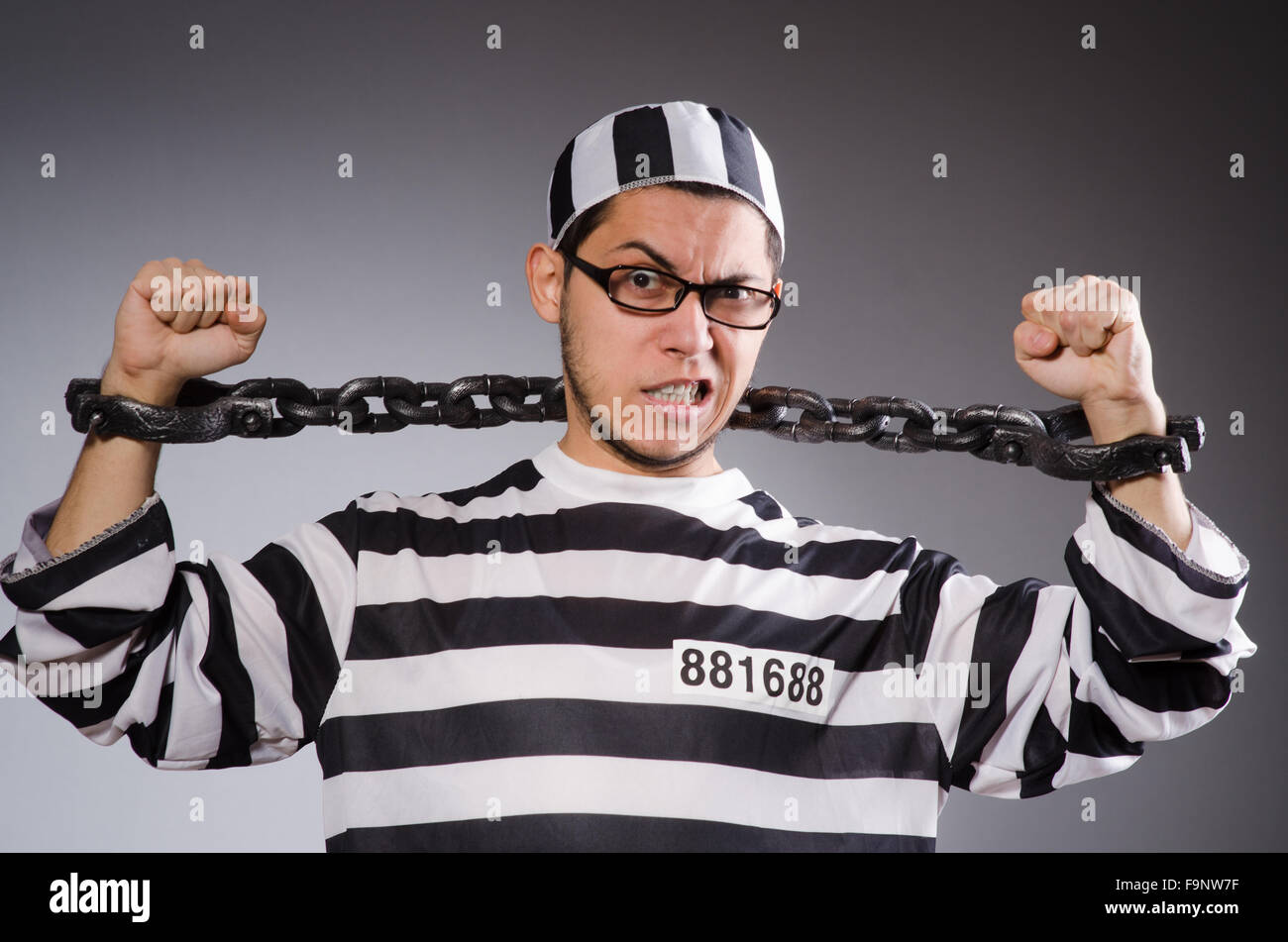 Young prisoner in chains against gray Stock Photo - Alamy