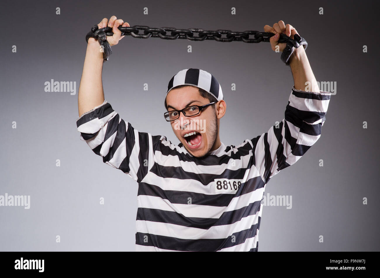 Young prisoner in chains against gray Stock Photo - Alamy