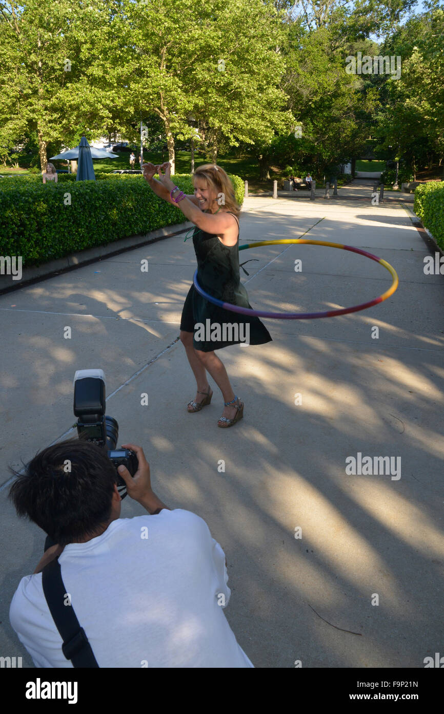 woman enjoys a hula hoop while a photographer takes pictures of her ...