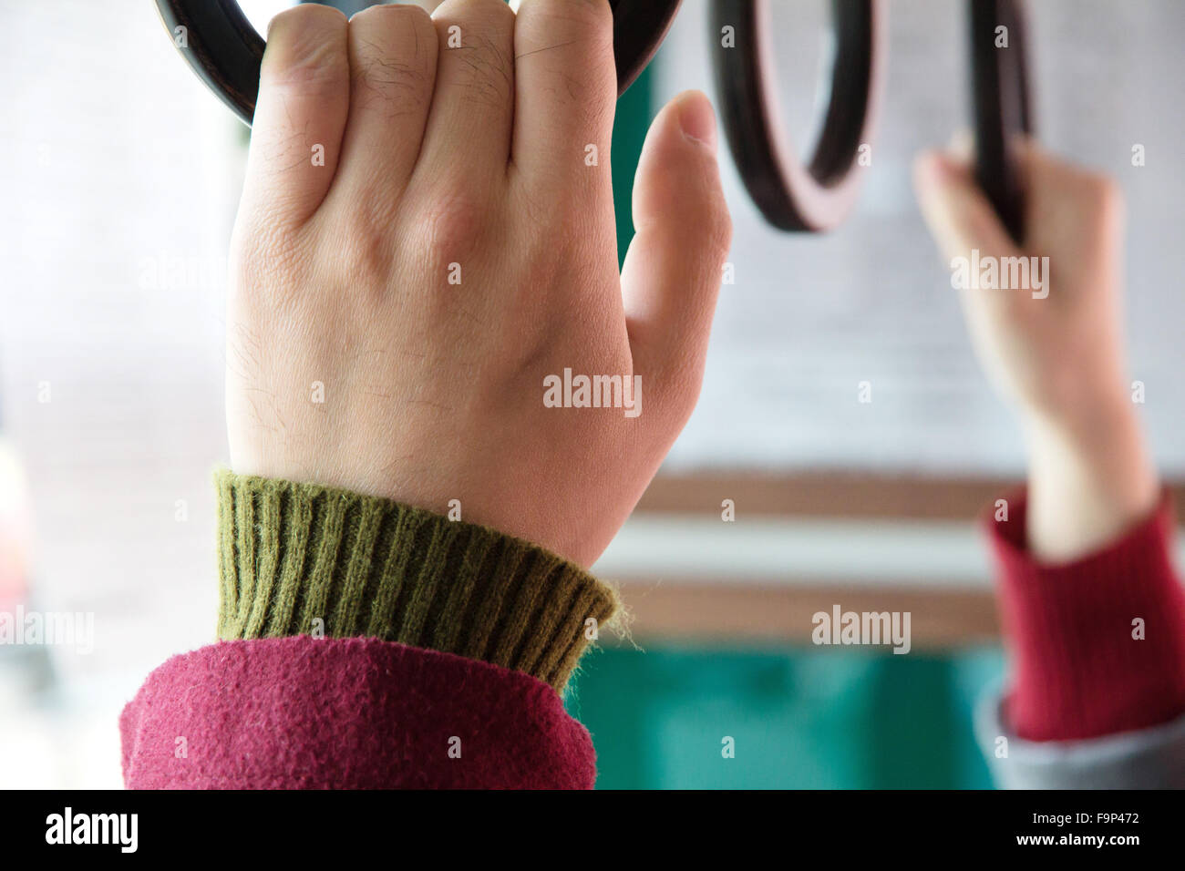 people holding onto a handle on a bus Stock Photo - Alamy