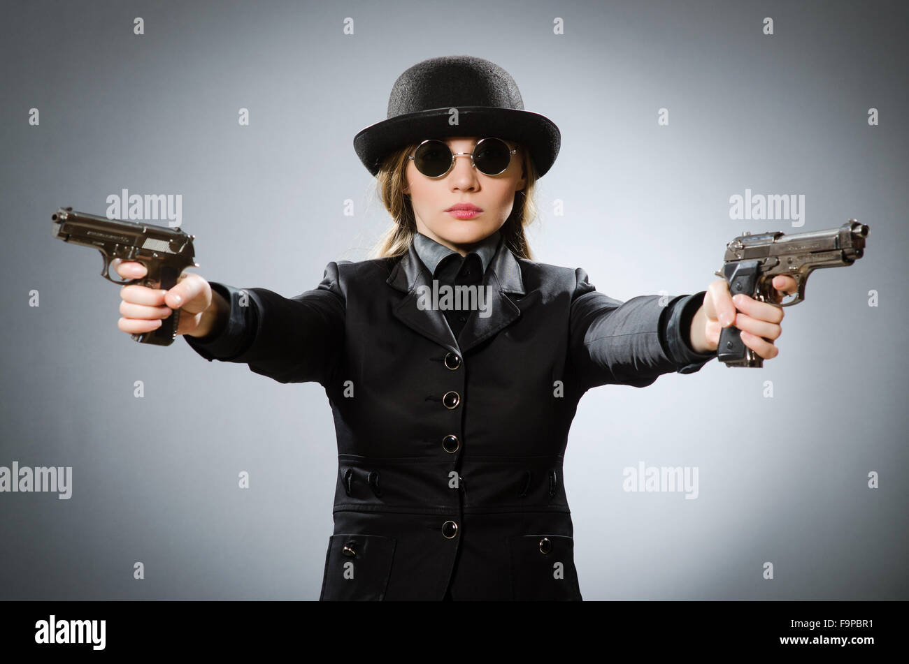 Female spy with weapon against gray Stock Photo - Alamy