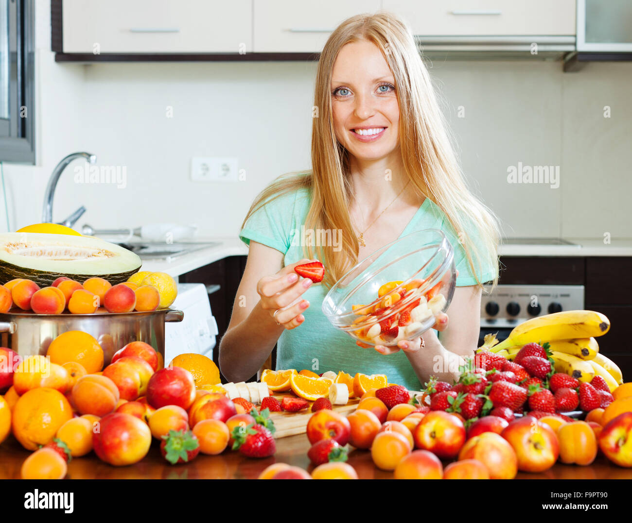 Smiling long-haired woman cooking fruit salad Stock Photo - Alamy