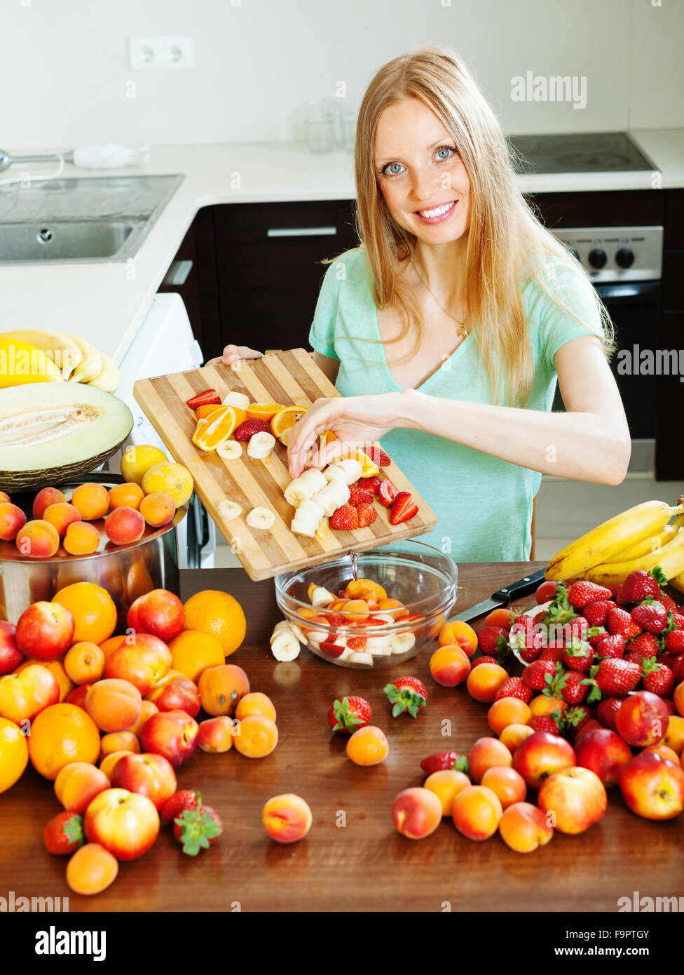 Casual long-haired girl cooking fruit salad with fruits Stock Photo - Alamy