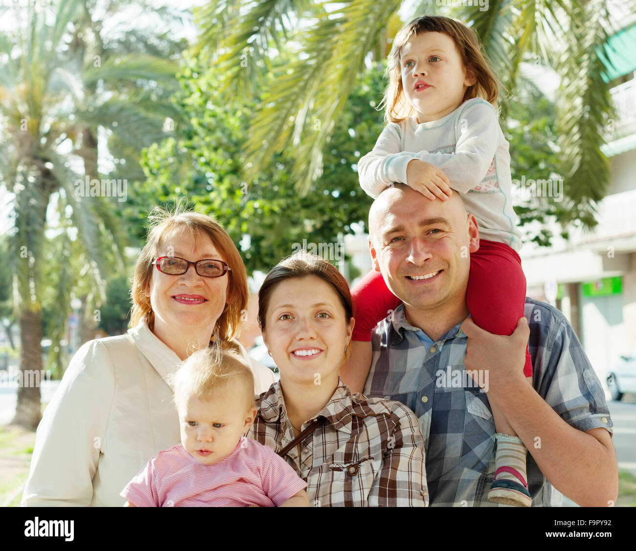 joyful parents with two children and grandmother at street in summer ...