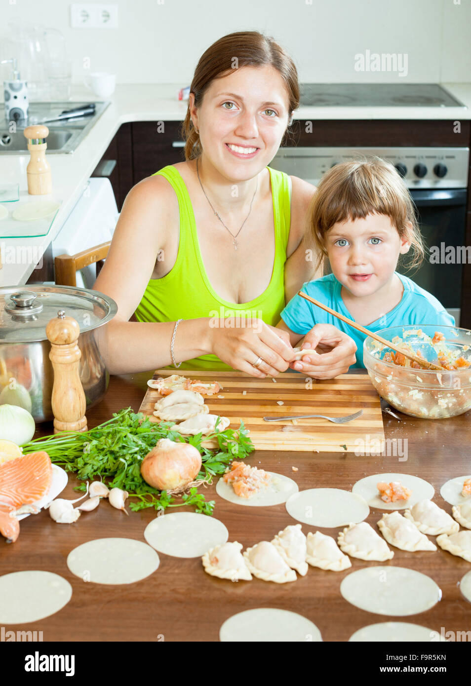 Happy mother with daughter making fish dumplings in a home large ...