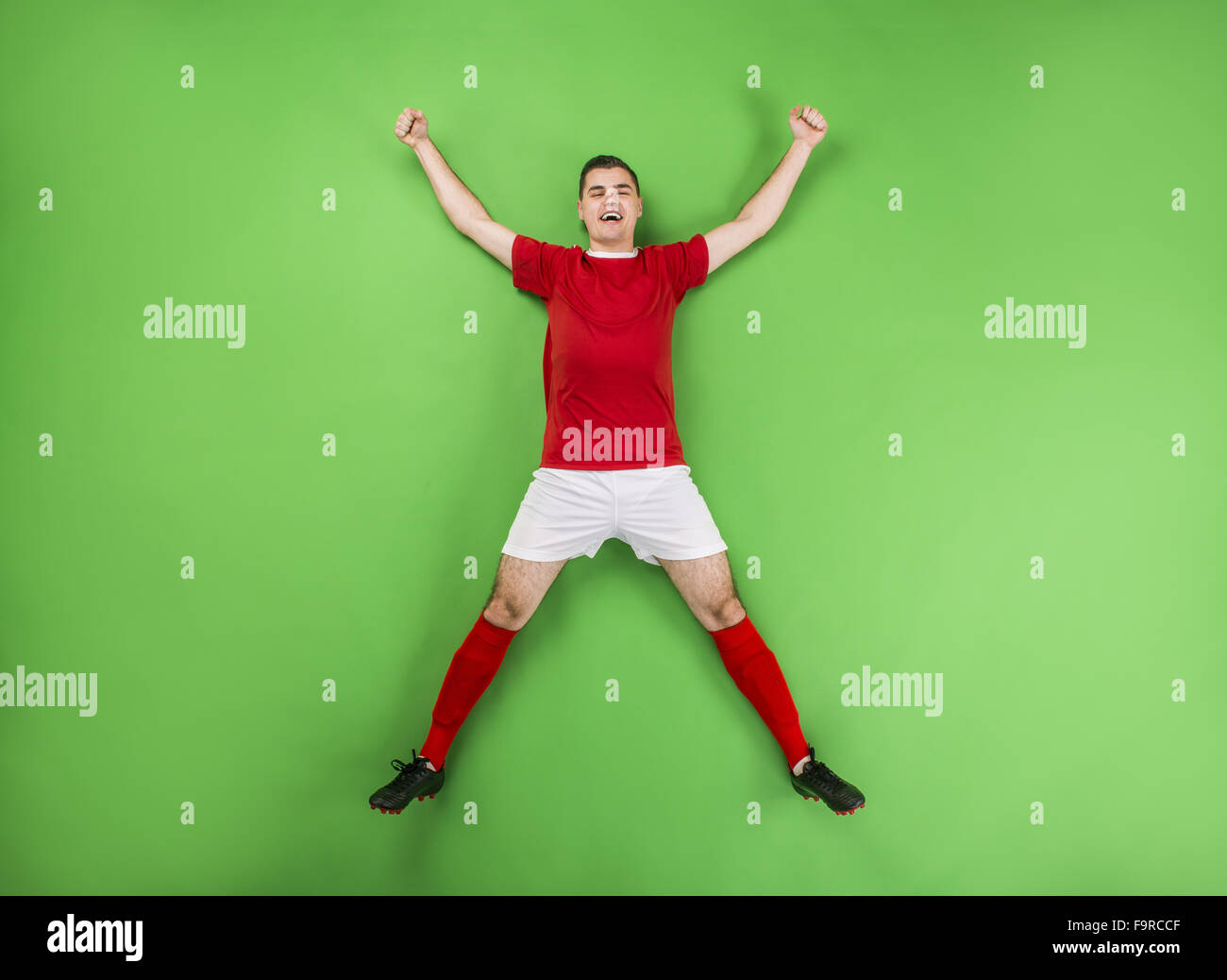 Happy football player celebrating victory. Studio shot on a green ...