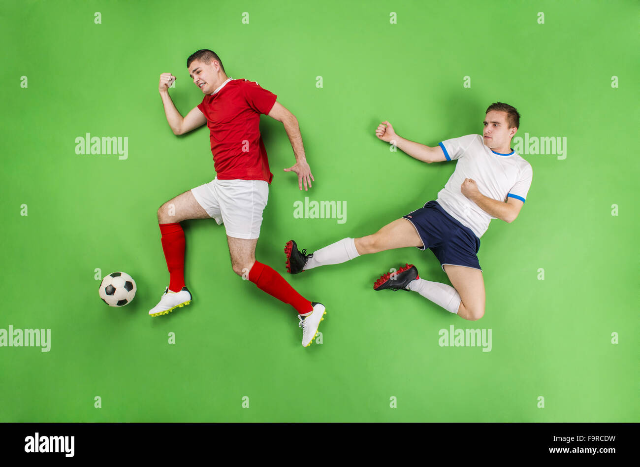 Two football players fighting for a ball. Studio shot on a green ...