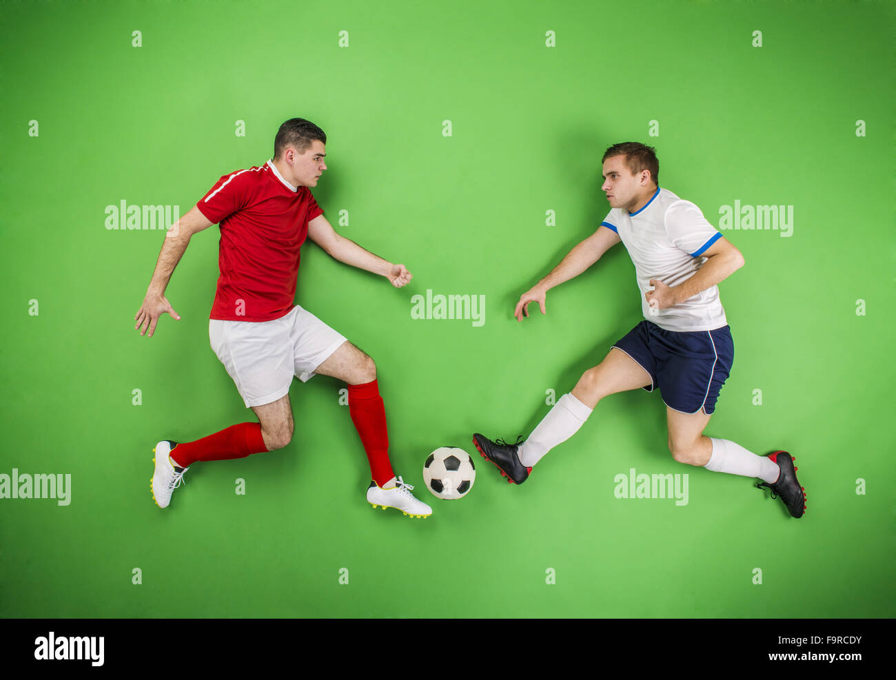 Two football players fighting for a ball. Studio shot on a green ...