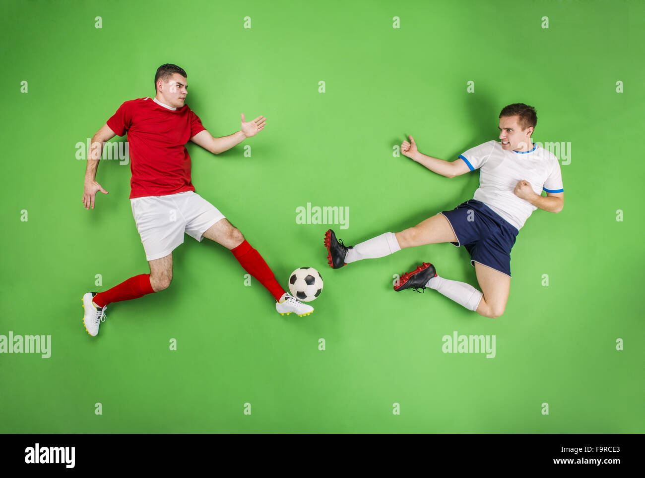 Two football players fighting for a ball. Studio shot on a green ...