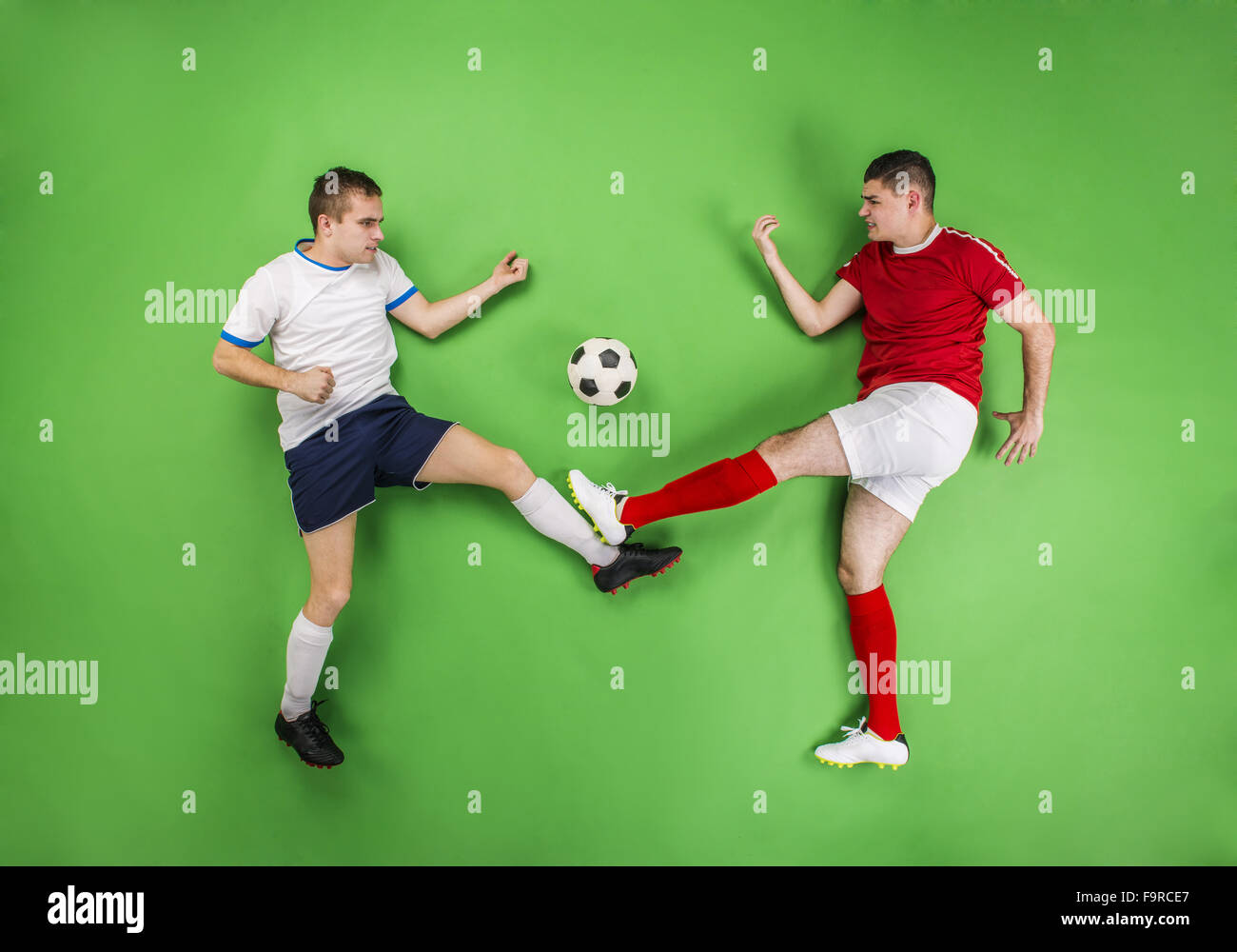 Two football players fighting for a ball. Studio shot on a green ...