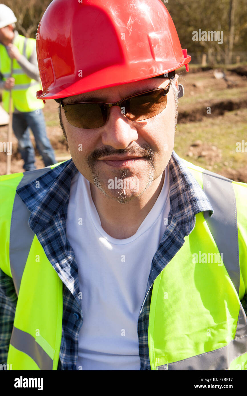 Male construction worker smiling at camera with partner working in ...