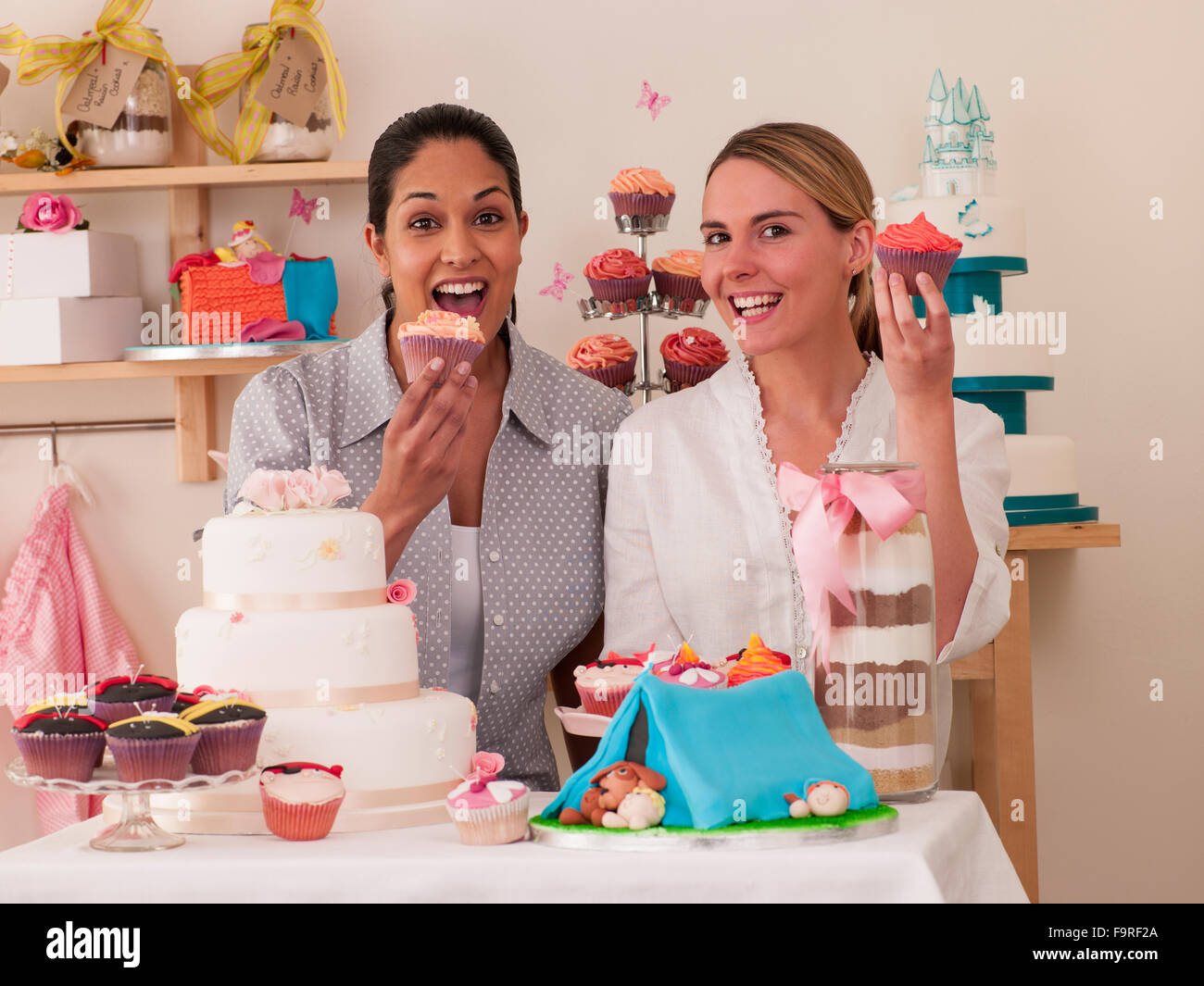 Two women playfully showing off cakes they have made Stock Photo - Alamy