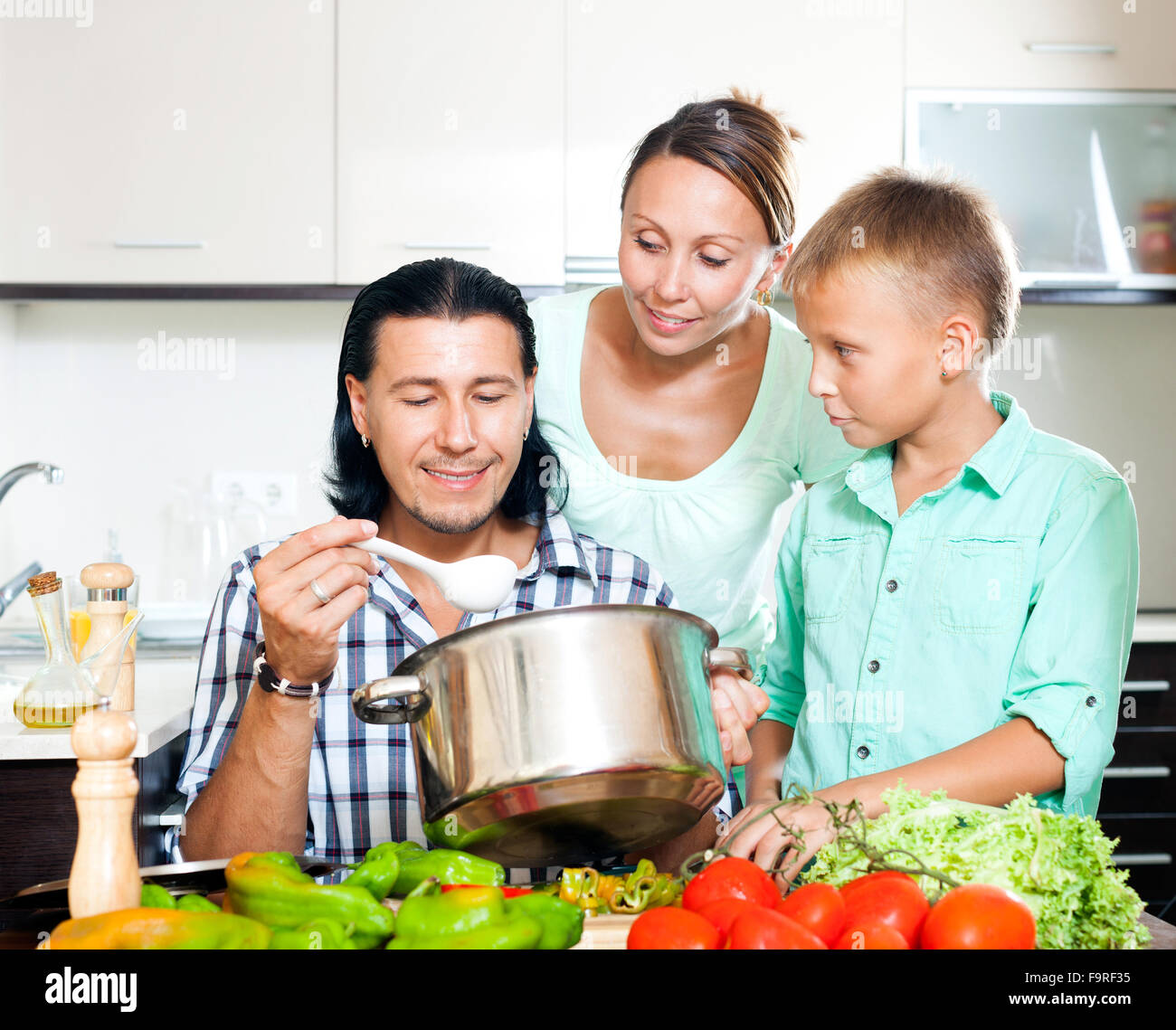 Happy smiling parents and teenager son tasting veggie lunch Stock Photo ...