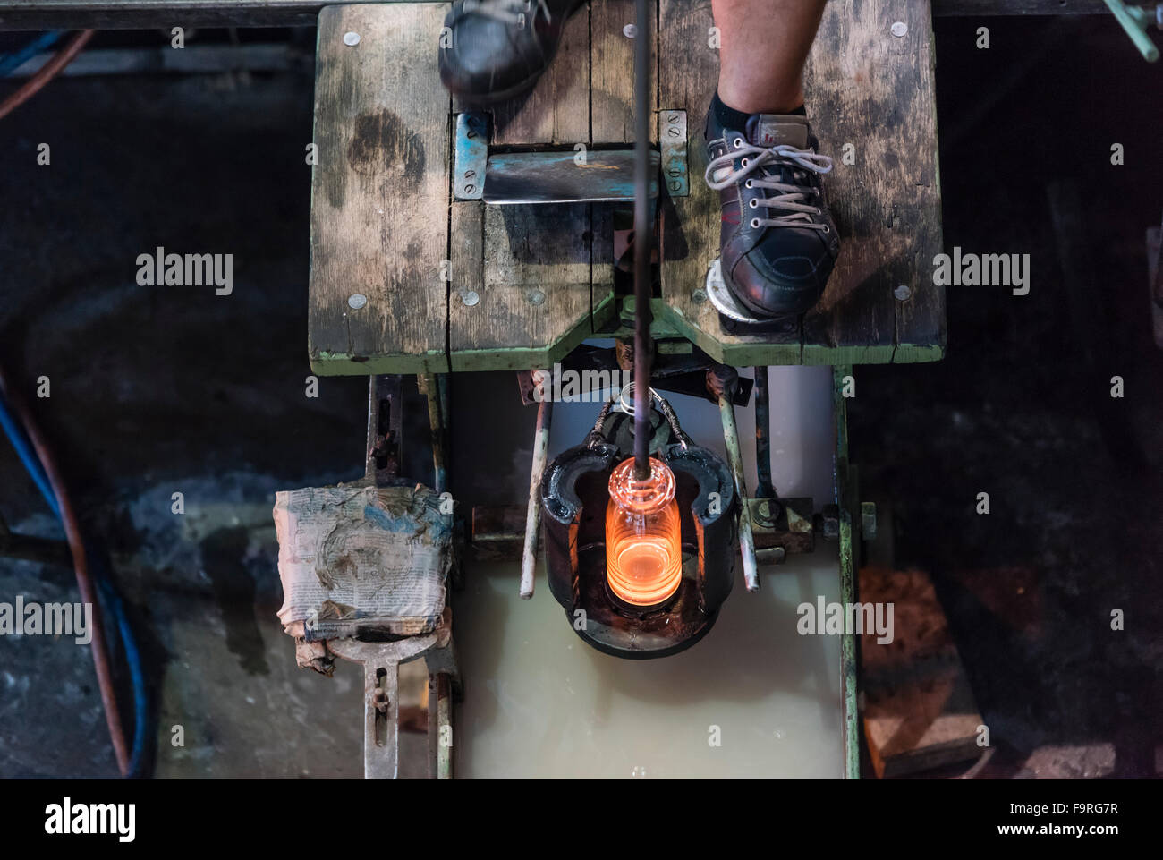 Melted glass, glowing red hot, being shaped in a mould at the ...