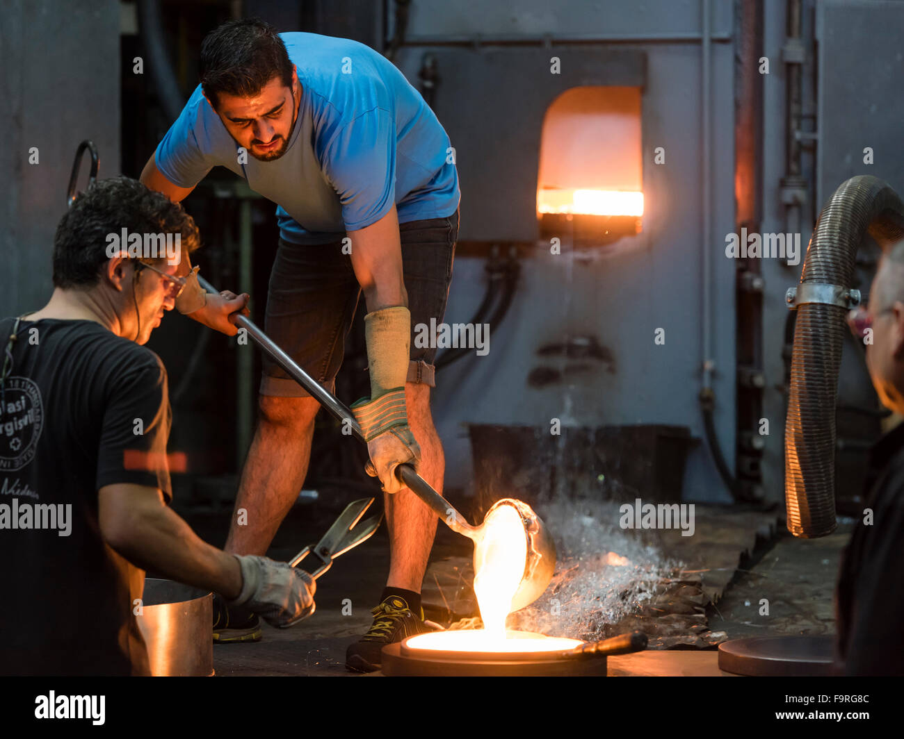 Glassblowers working in front of the furnace at the glass factory ...