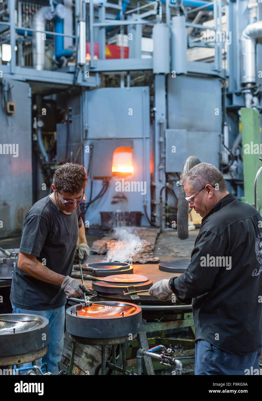 Glassblowers working in front of the furnace at the glass factory ...