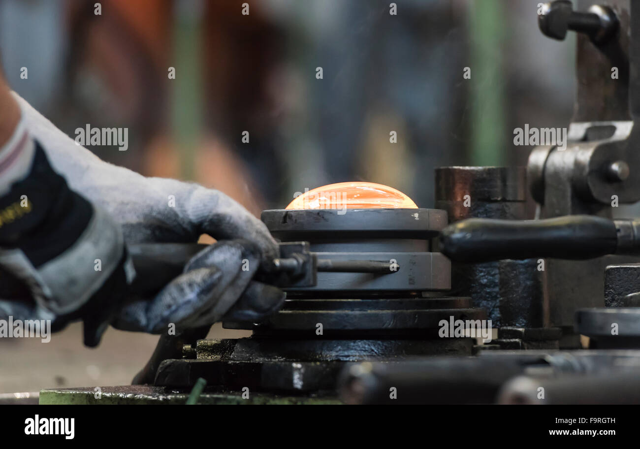 A glassblower working in front of the furnace at the glass factory ...