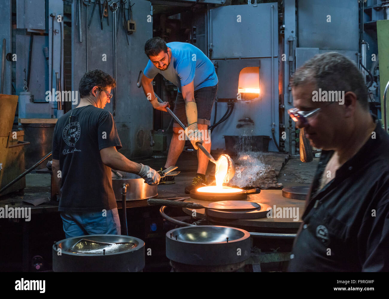 Glassblowers working in front of the furnace at the glass factory ...