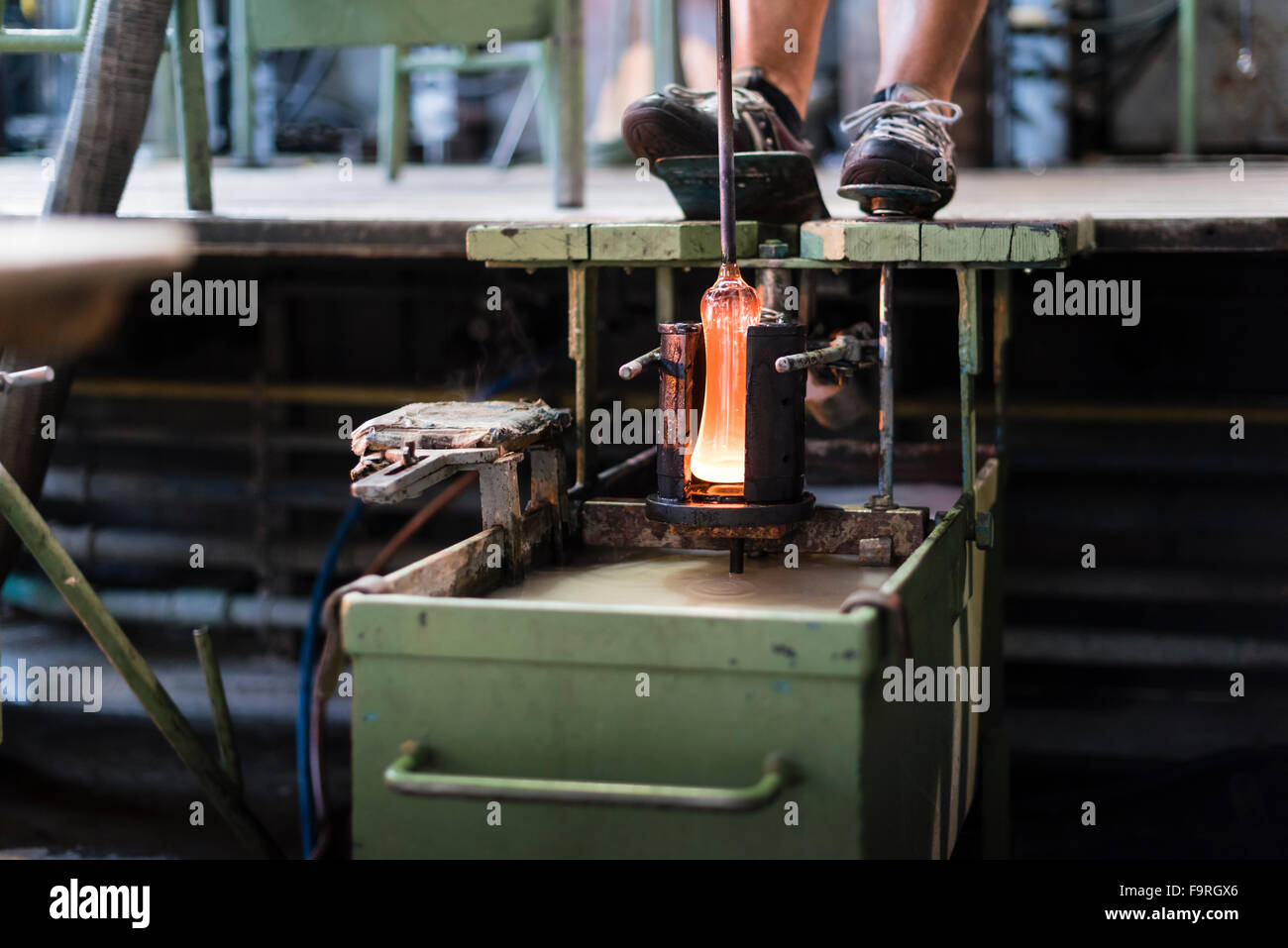 Melted glass, glowing red hot, is being shaped in a mould at the ...