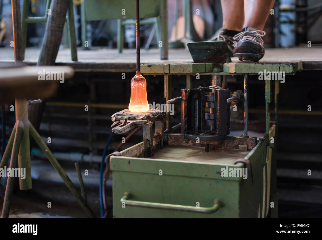 Melted glass, glowing red hot, is being shaped in a mould at the ...