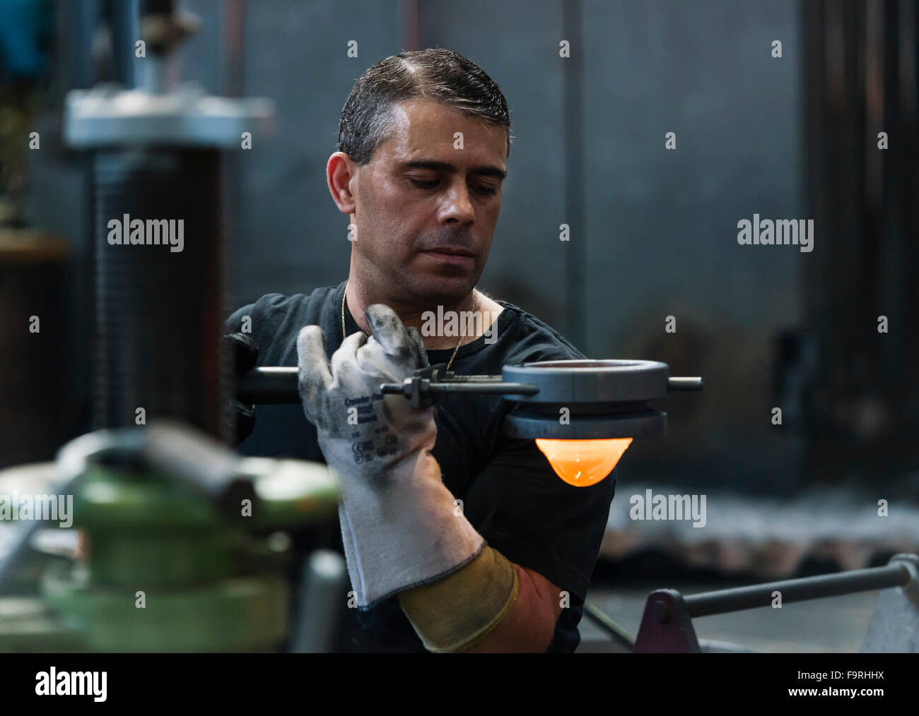 A glassblower working in front of the furnace at the glass factory ...
