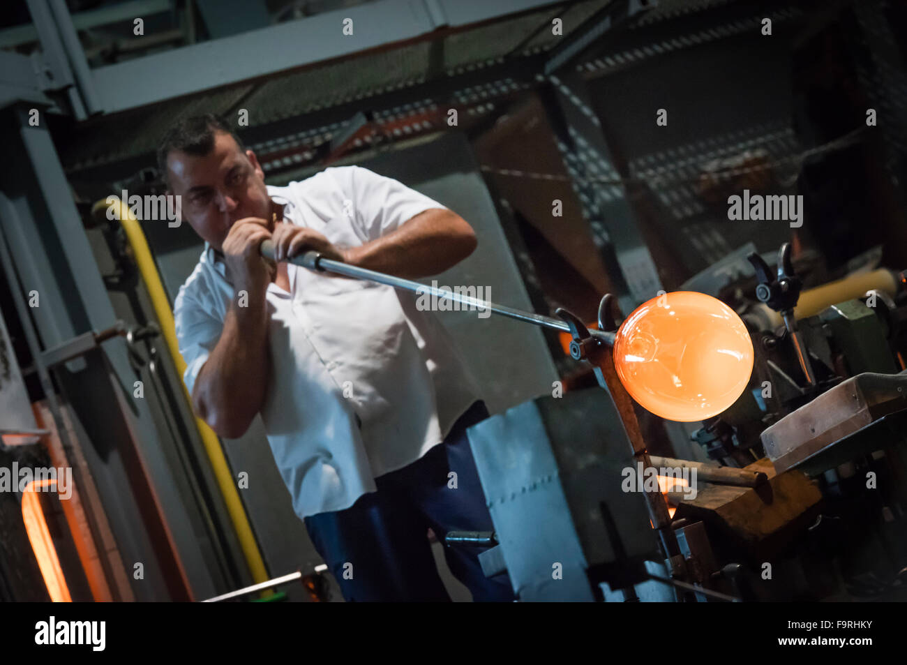 A glassblower at work in front of the furnace of the traditional ...
