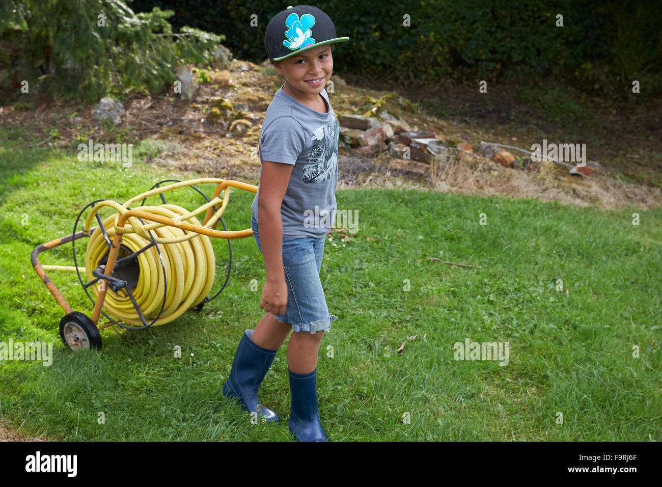 9-year-old boy pulling a garden hose Stock Photo - Alamy
