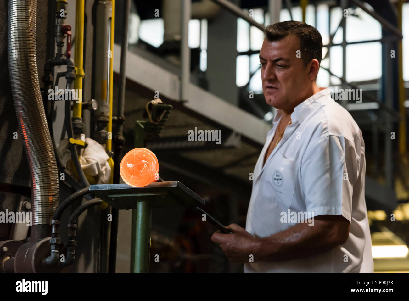A glassblower at work in front of the furnace of the traditional ...