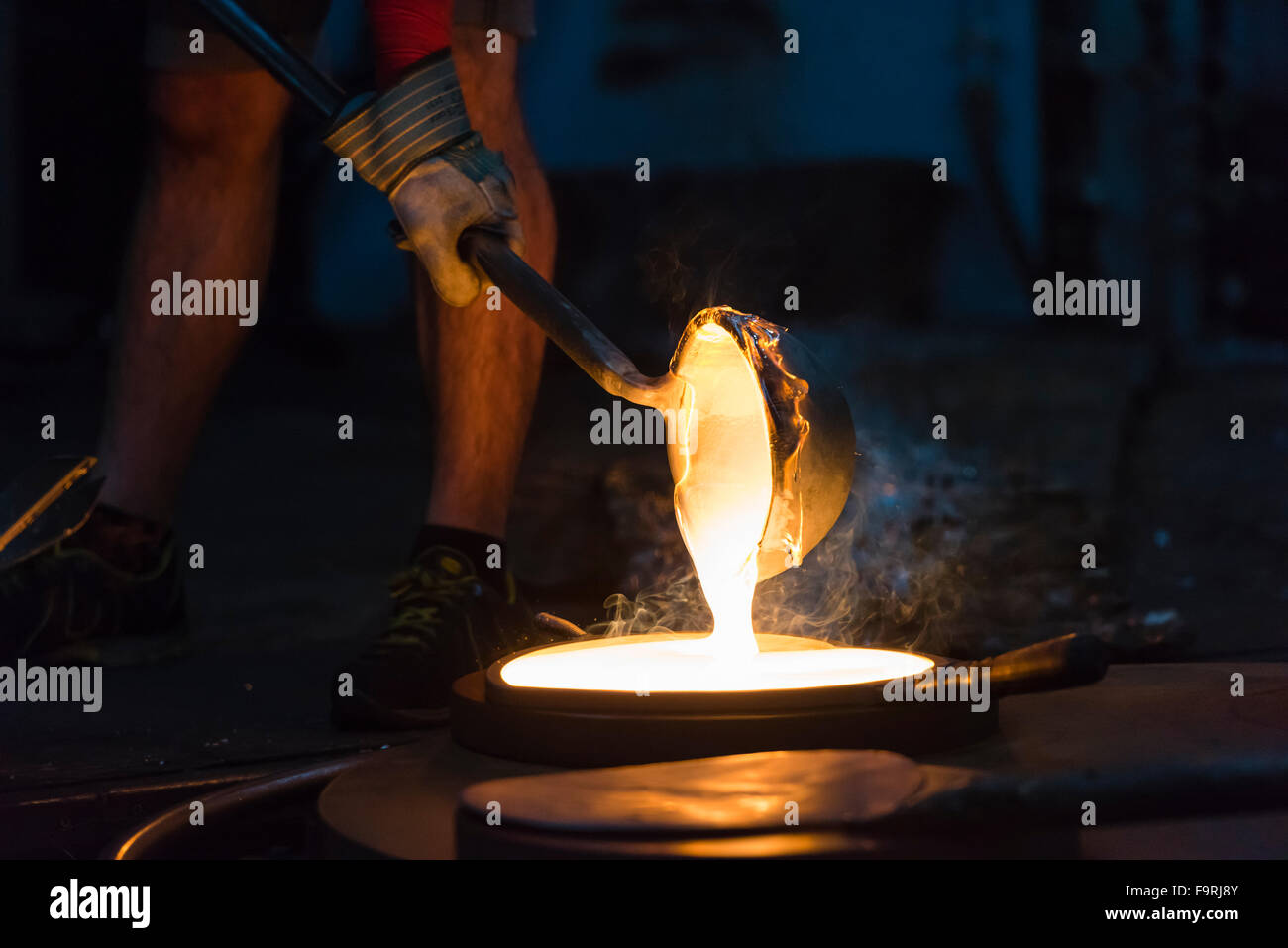 Glassblowers working in front of the furnace at the glass factory ...