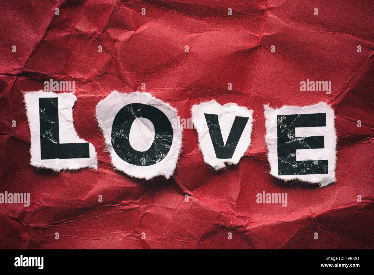 Torn word «Love» on a crumpled red background Stock Photo - Alamy