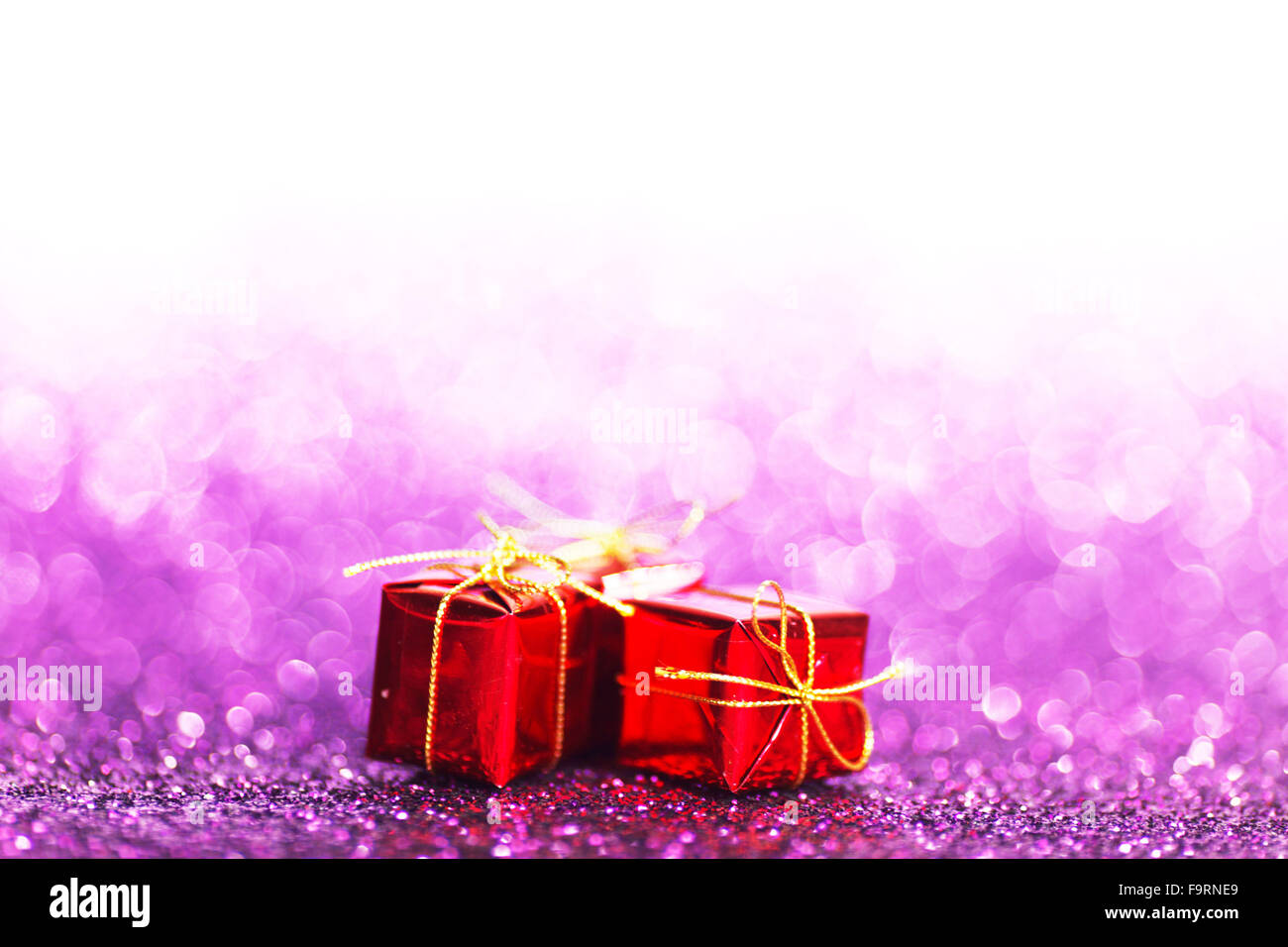 Small decorative gift boxes on shiny glitter background Stock Photo - Alamy