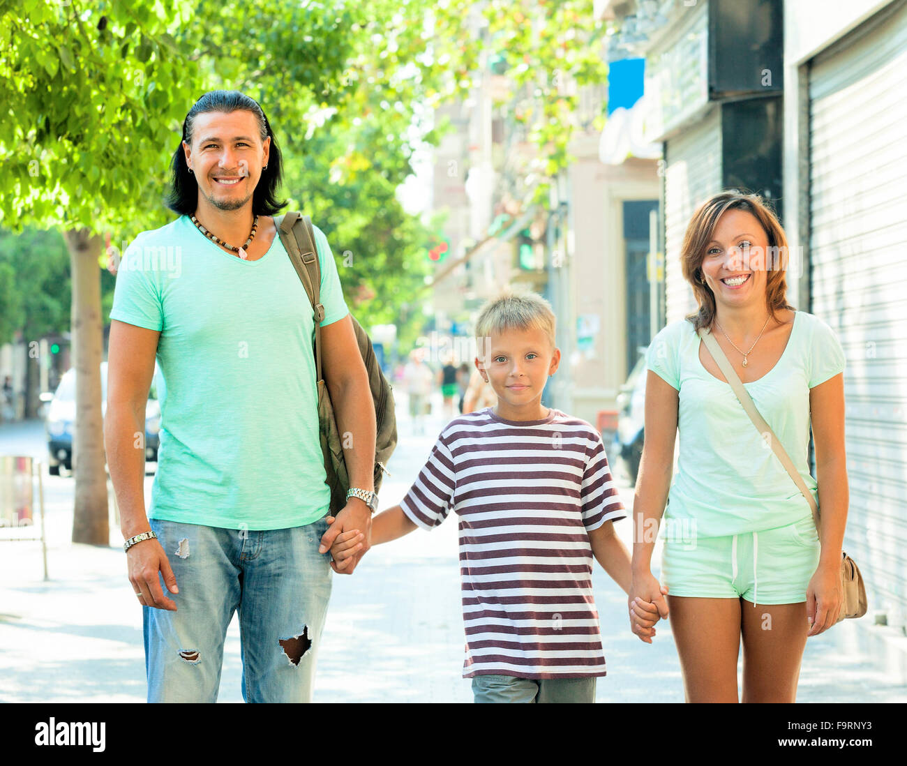 Happy parents with child walking in summer street Stock Photo - Alamy