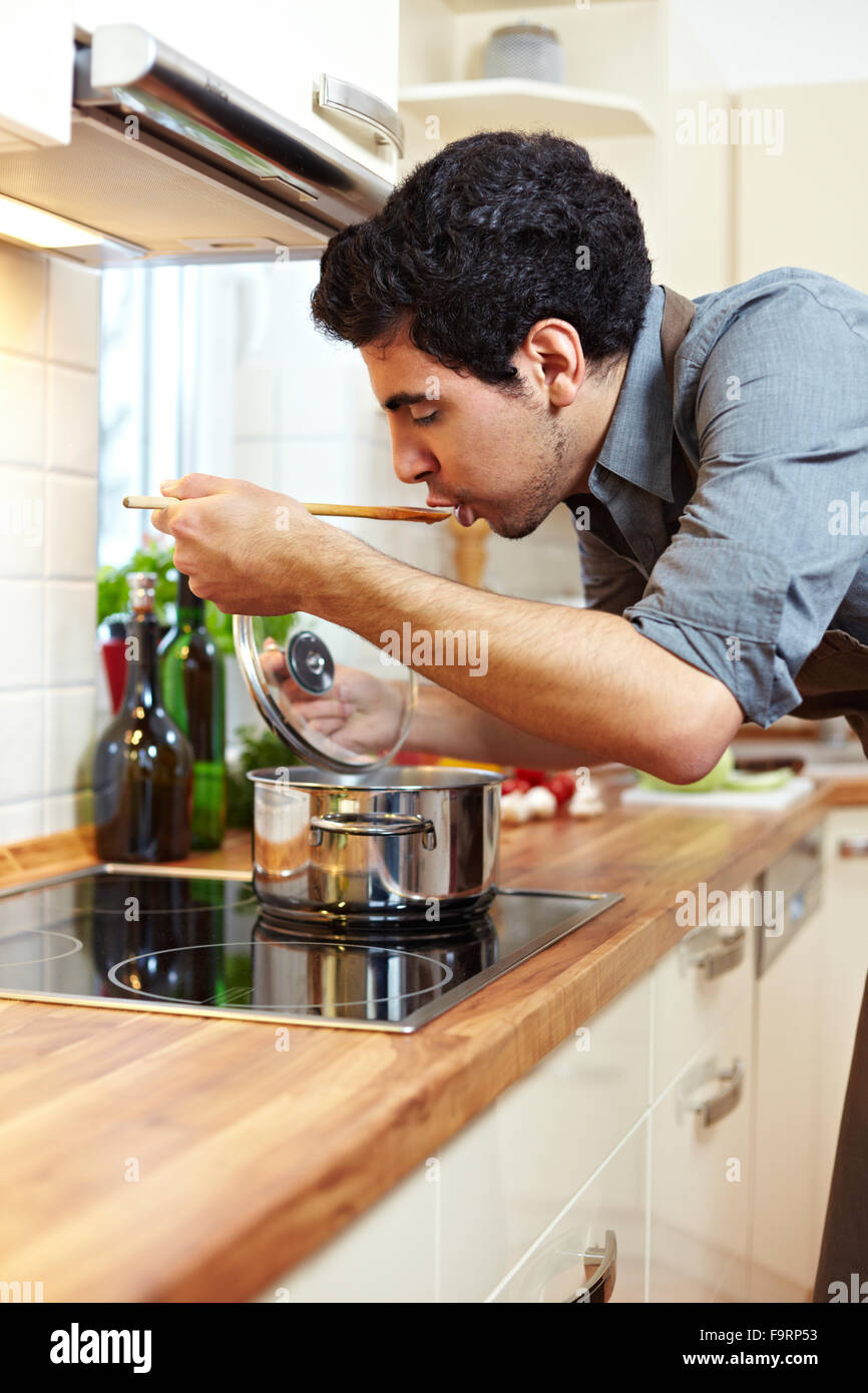 Homemaker in kitchen tasting soup on stove Stock Photo - Alamy