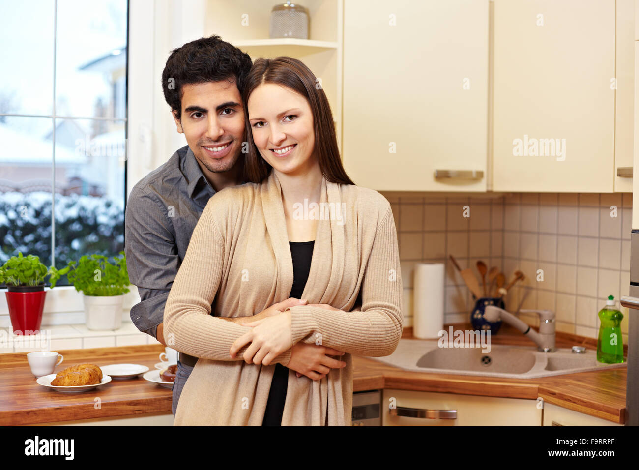 Happy smiling young couple standing in a kitchen Stock Photo - Alamy