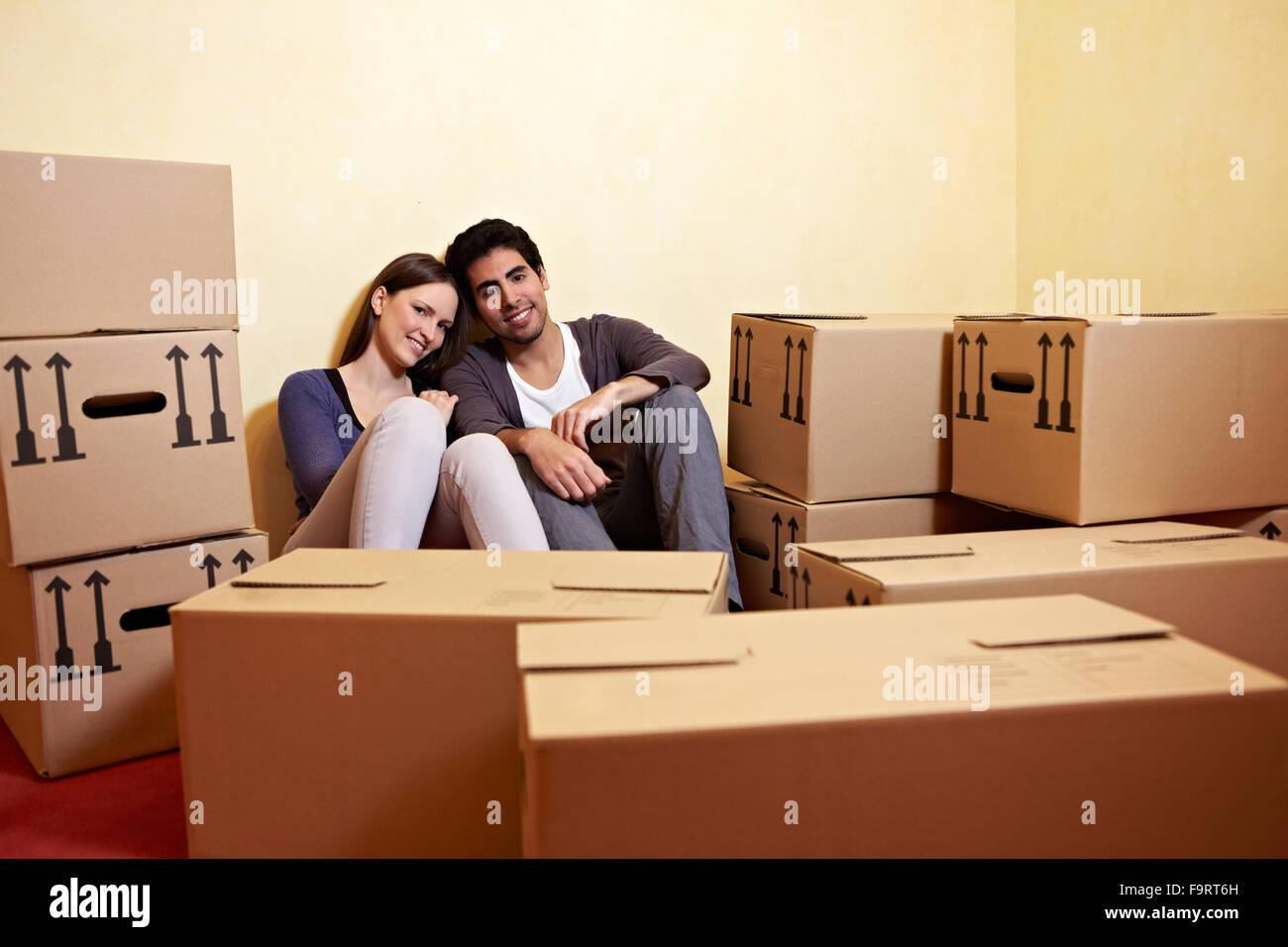 Tired couple sitting between many boxes in their new home Stock Photo ...