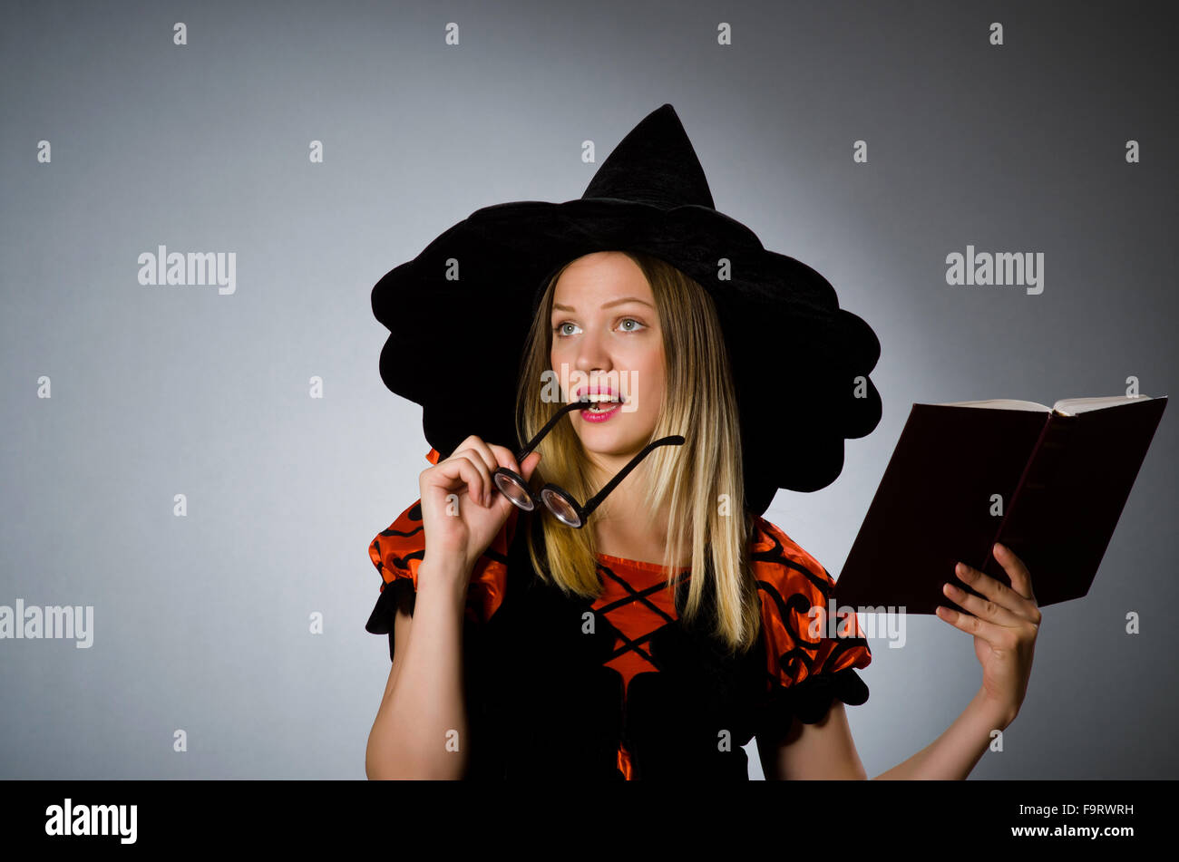 Witch with book in dark studio Stock Photo - Alamy