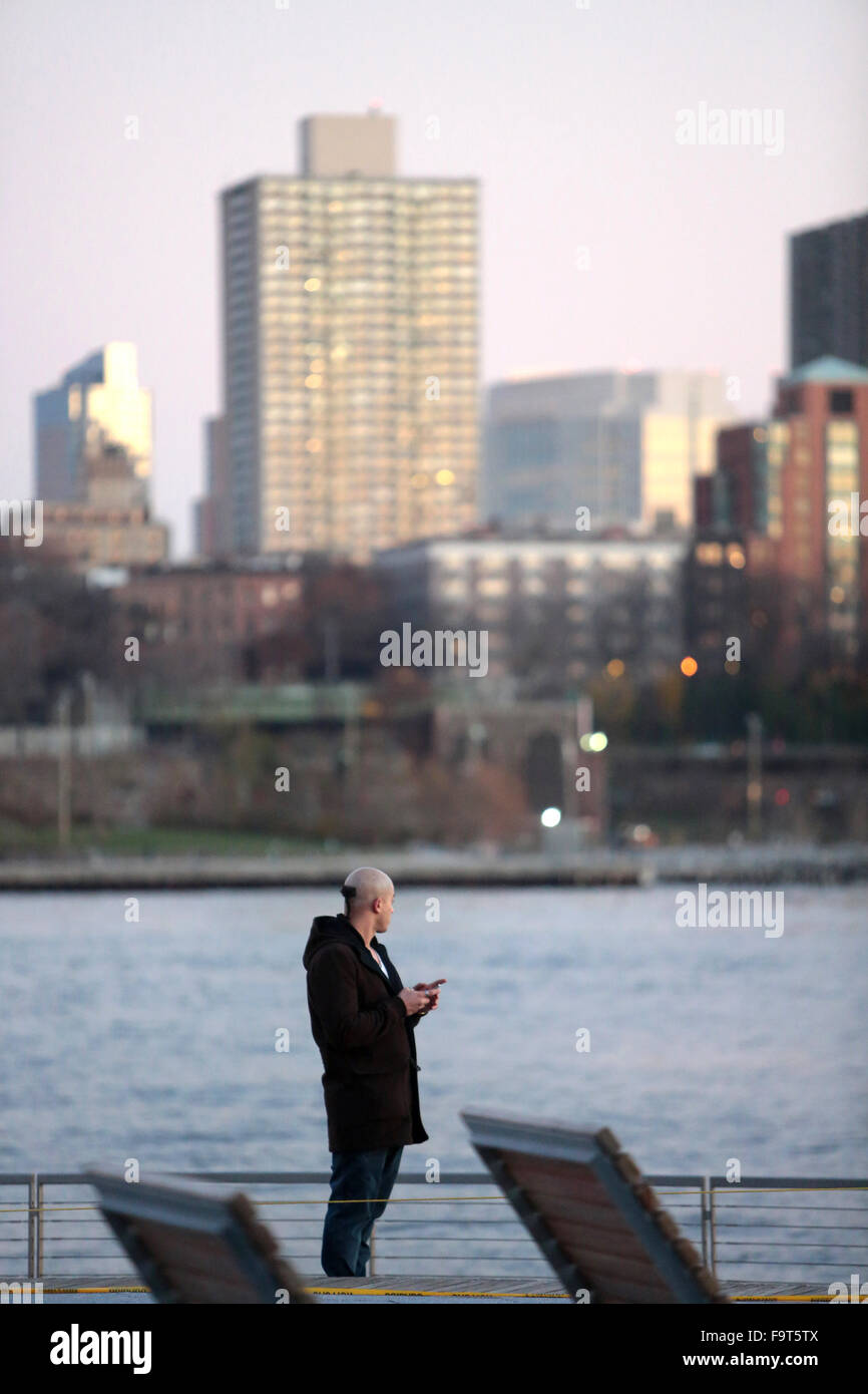 Man looking at the Manhattan skyline from the Hudson River Stock Photo ...