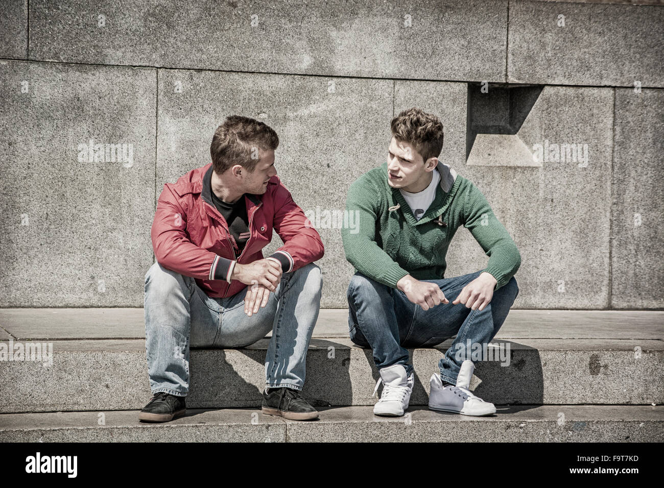 Two young men talking while sitting on curb. Summertime Stock Photo - Alamy Two young men talking while sitting on curb. Summertime Stock Photo - Alamy