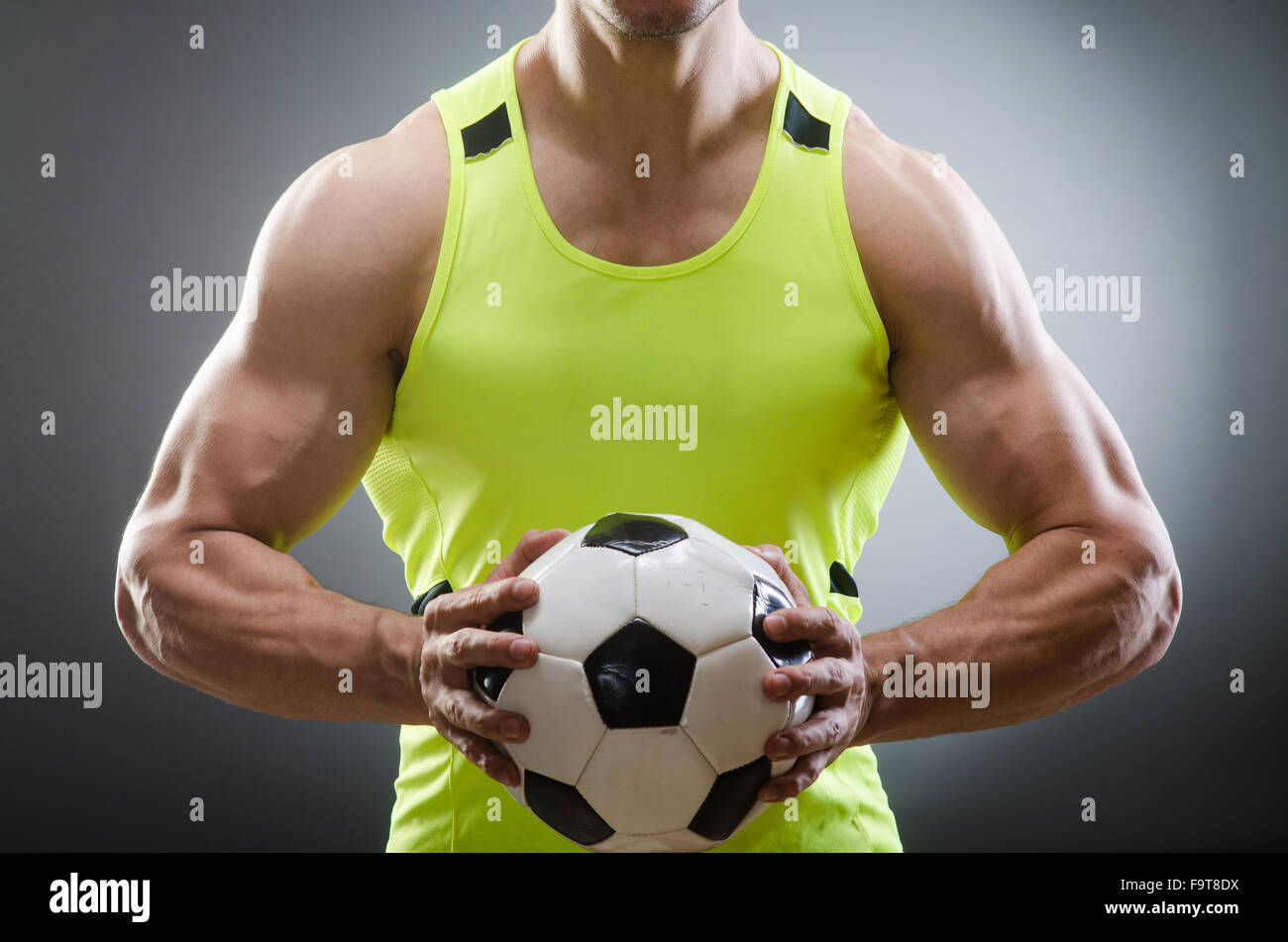 Muscular man with football ball Stock Photo - Alamy