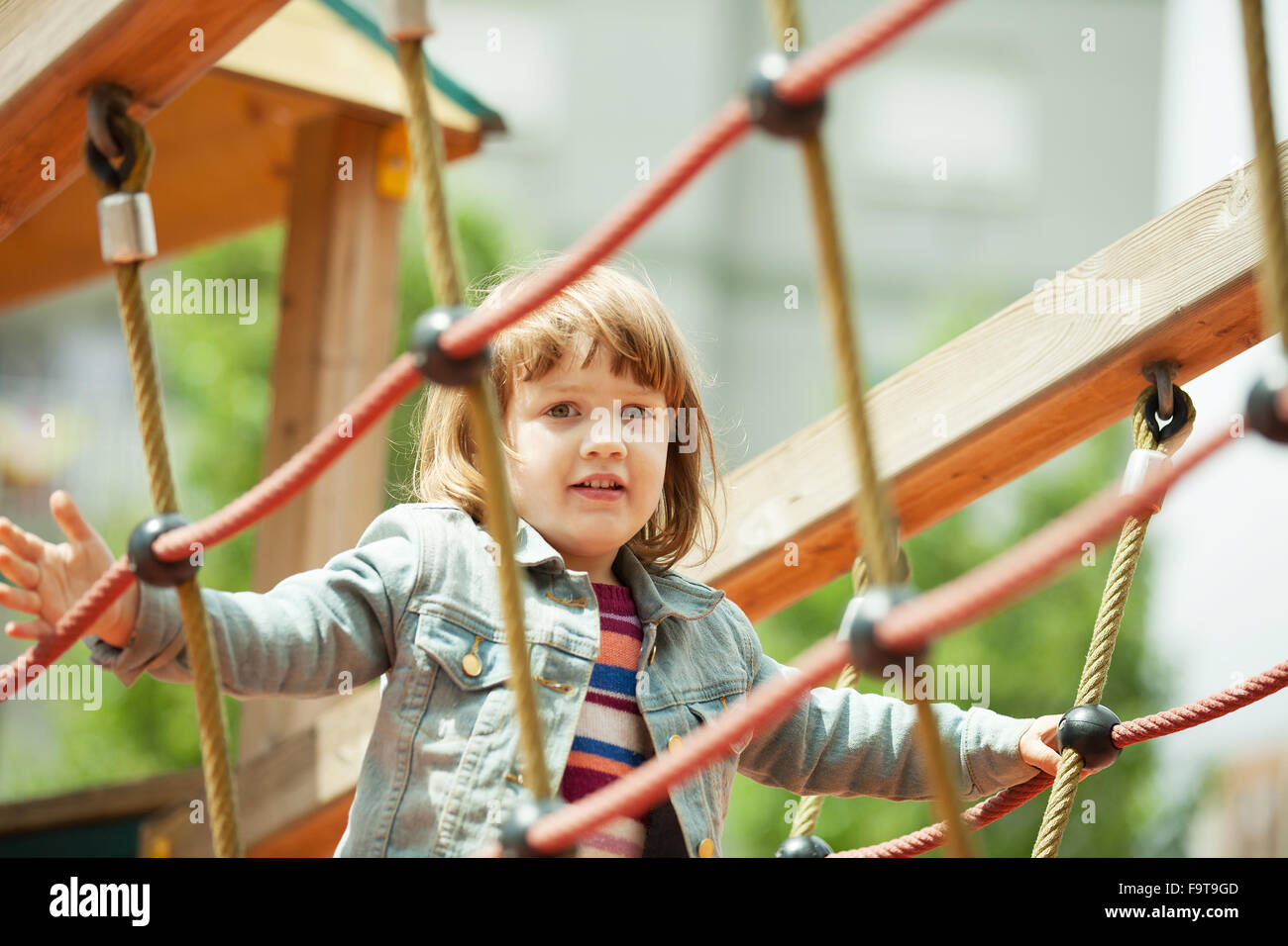 baby girl climbs the ropes on the playground Stock Photo - Alamy