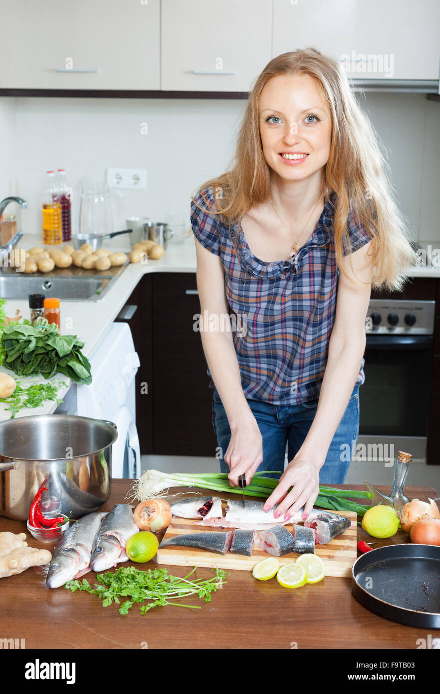Happy blonde woman slicing raw fish at kitchen Stock Photo - Alamy