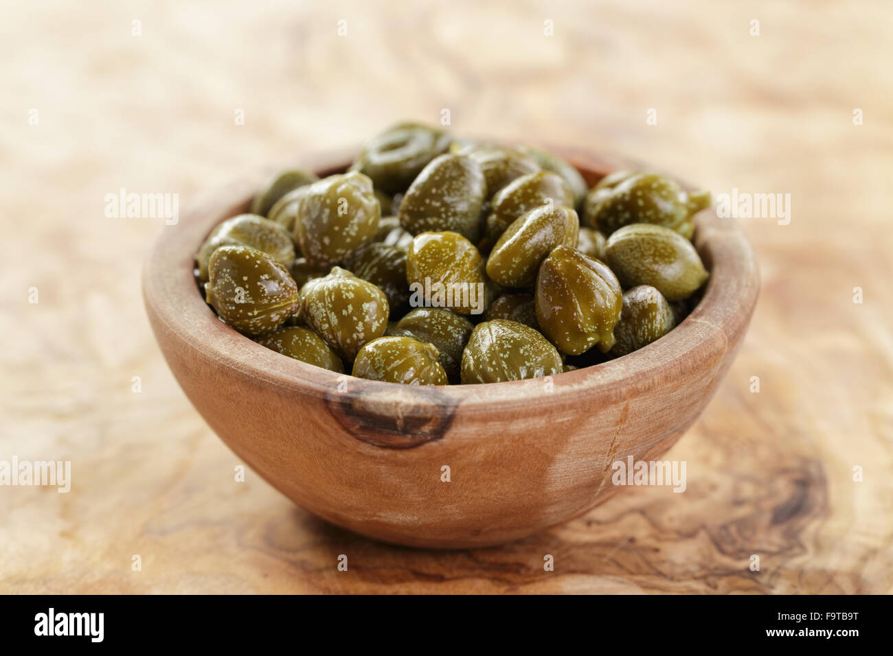 marinated capers in olive bowl on wood table Stock Photo - Alamy