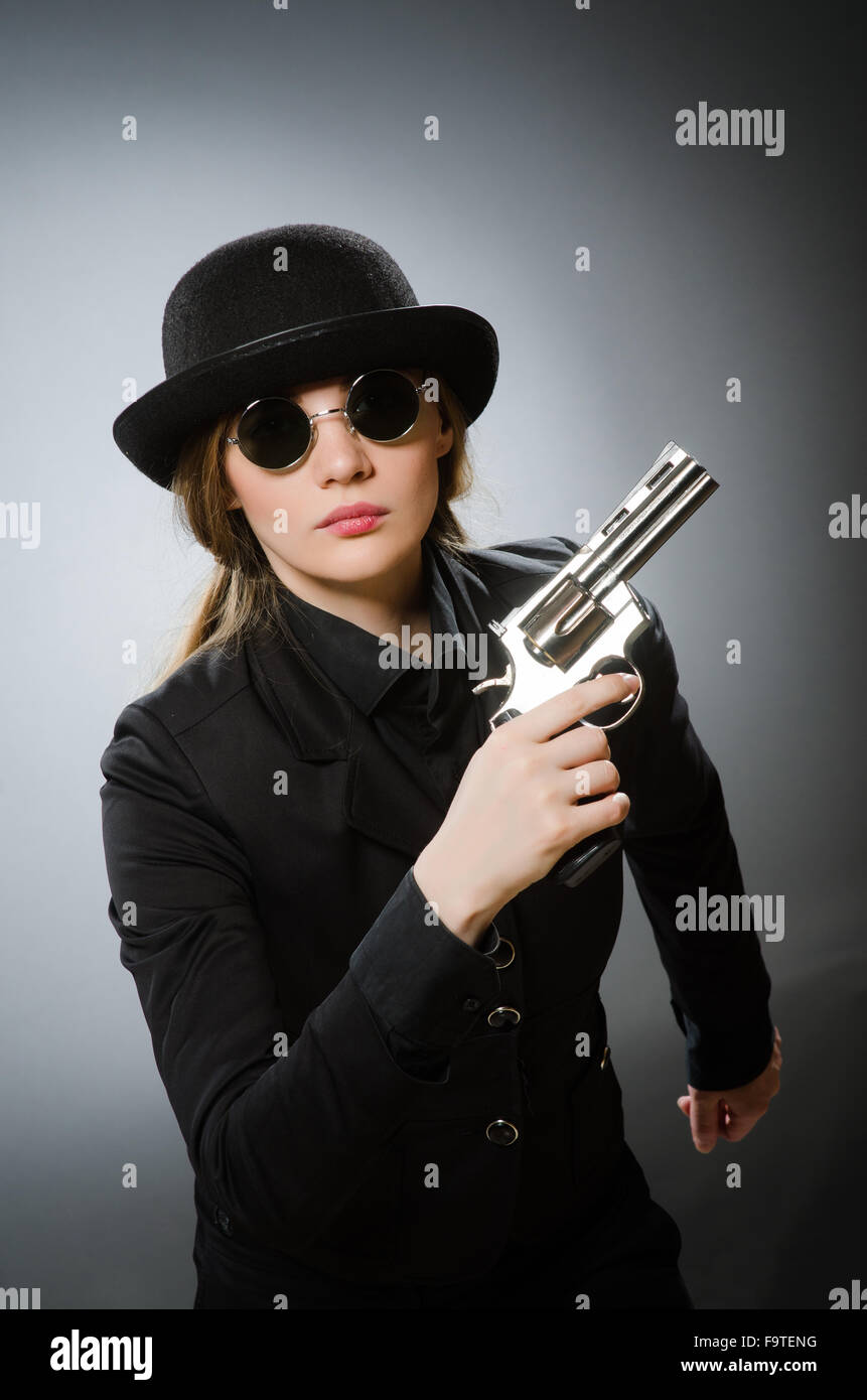 Female spy with weapon against gray Stock Photo - Alamy