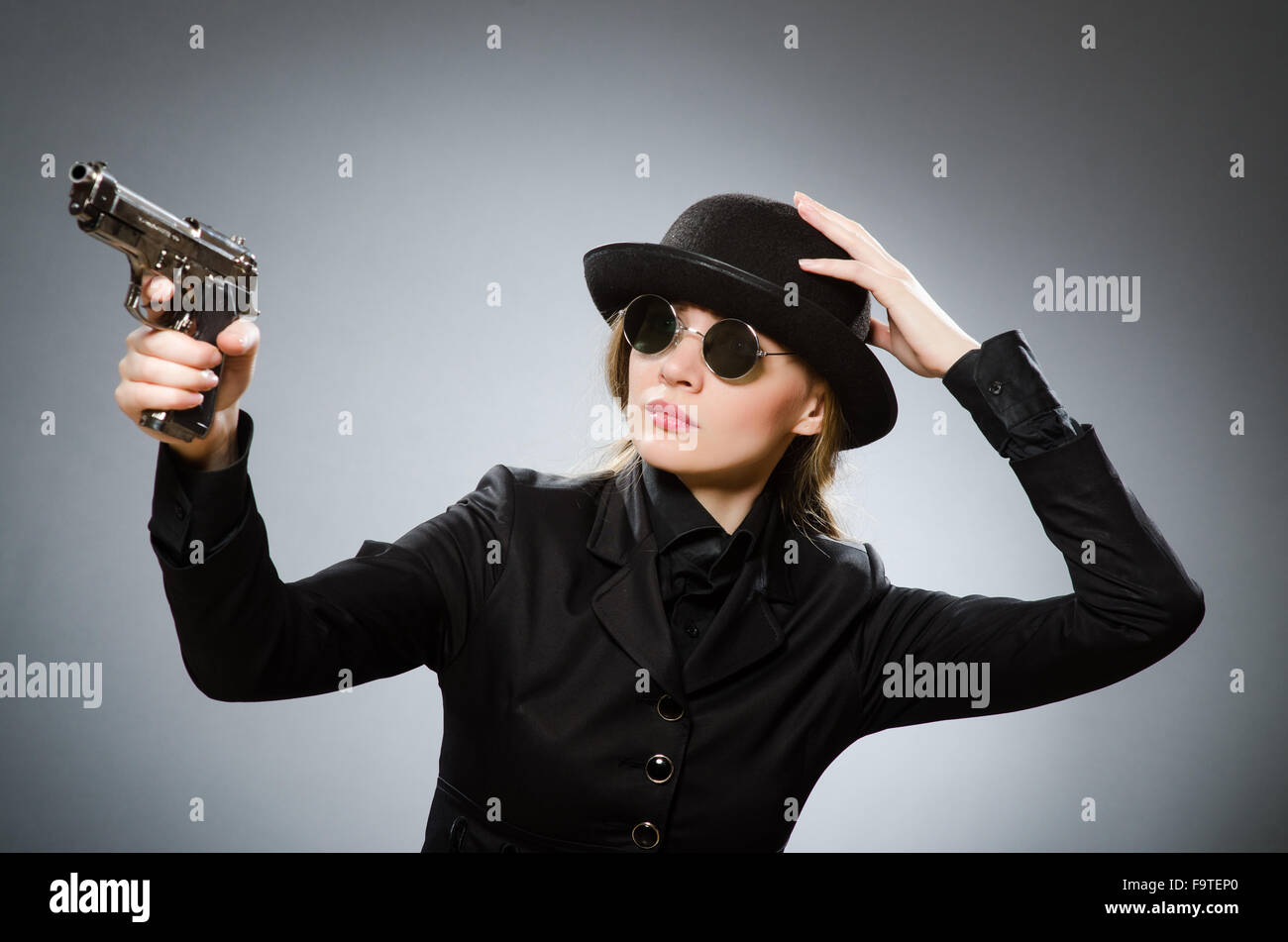 Female spy with weapon against gray Stock Photo - Alamy