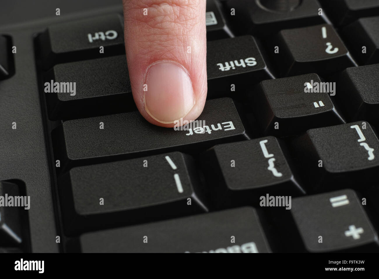 Finger pushing Enter key on black keyboard Stock Photo - Alamy